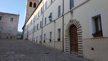 Uma rua de calçada com edifícios históricos, uma torre e um arco de pedra.
