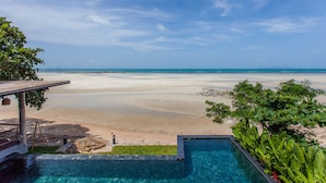 Vista da piscina com vista para a praia e céu claro.