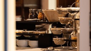 Disposição de buffet com várias estações de servir, incluindo tigelas e pratos, organizada sobre uma mesa.