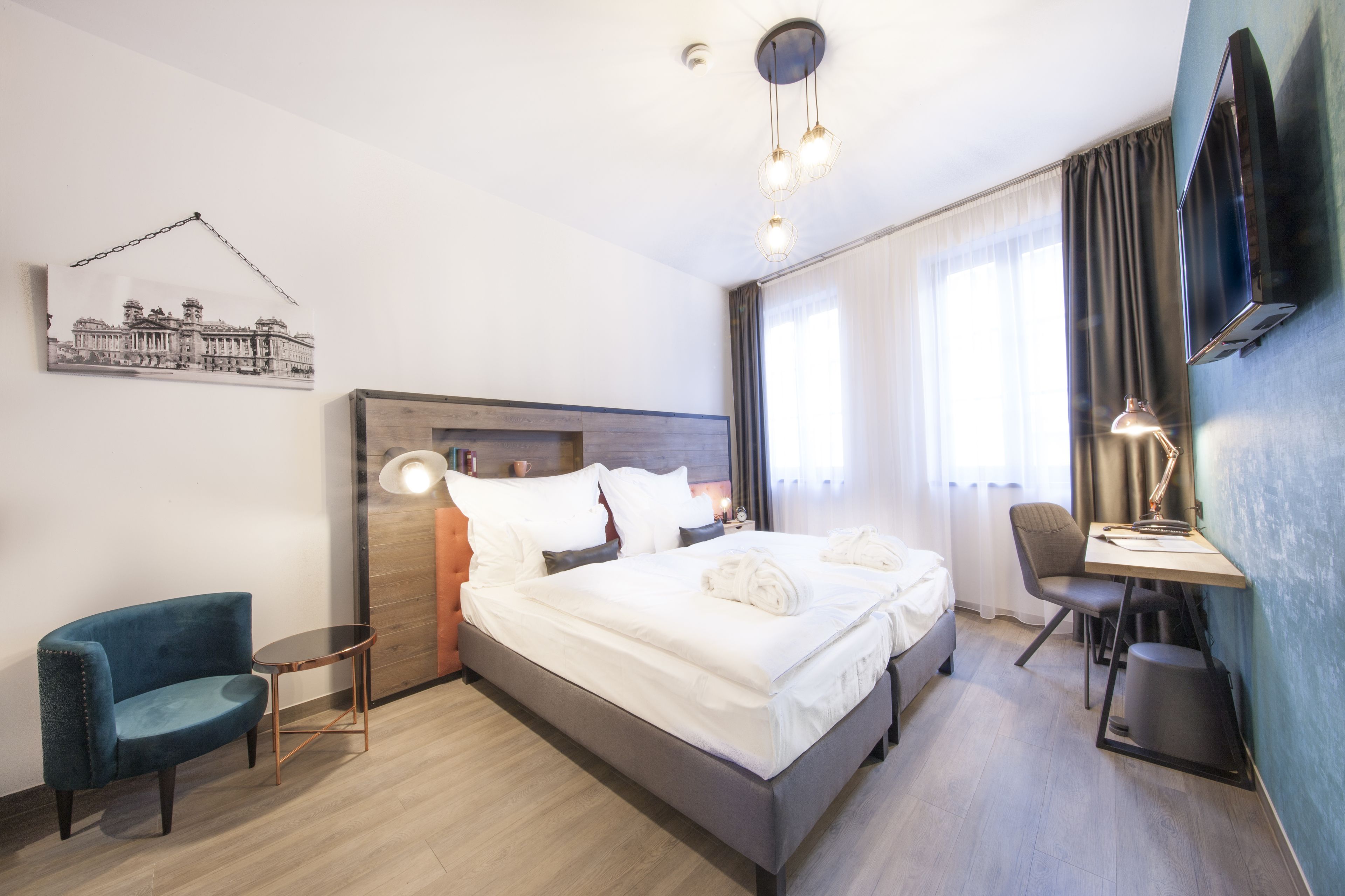 Quarto de hotel moderno com uma cama grande, uma escrivaninha, uma cadeira e uma televisão.