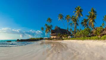 Na praia, areia branca, espreguiçadeiras, guarda-sóis