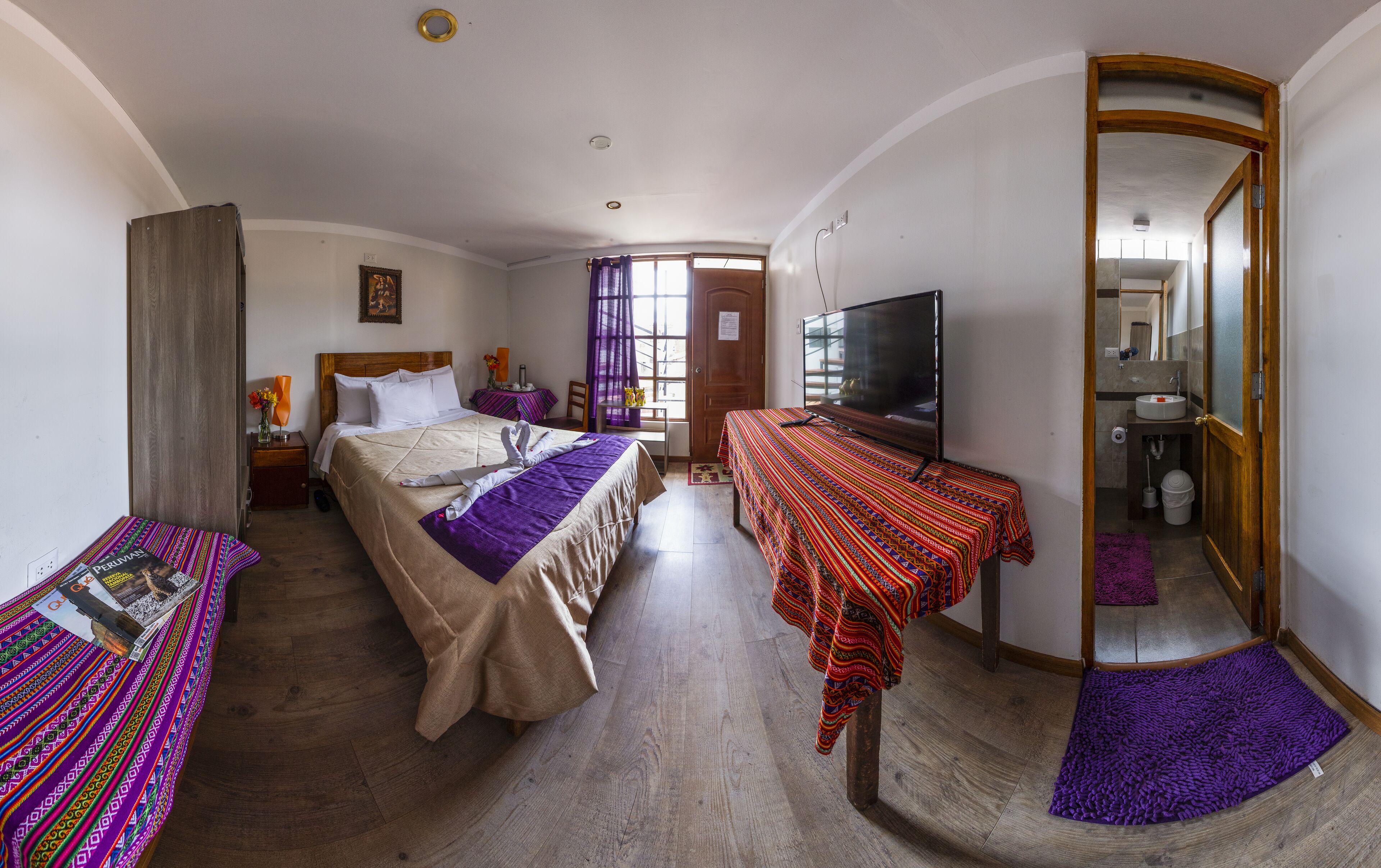 Quarto de hotel com duas camas, televisão, banheiro e vista para o exterior.