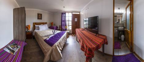 Quarto de hotel com duas camas, televisão, banheiro e vista para o exterior.