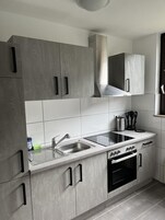 Cozinha moderna com armários cinza, uma pia de aço inoxidável e um forno.