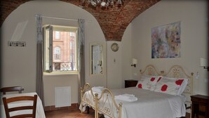 Quarto com cama, cadeira, janela, relógio e quadro.