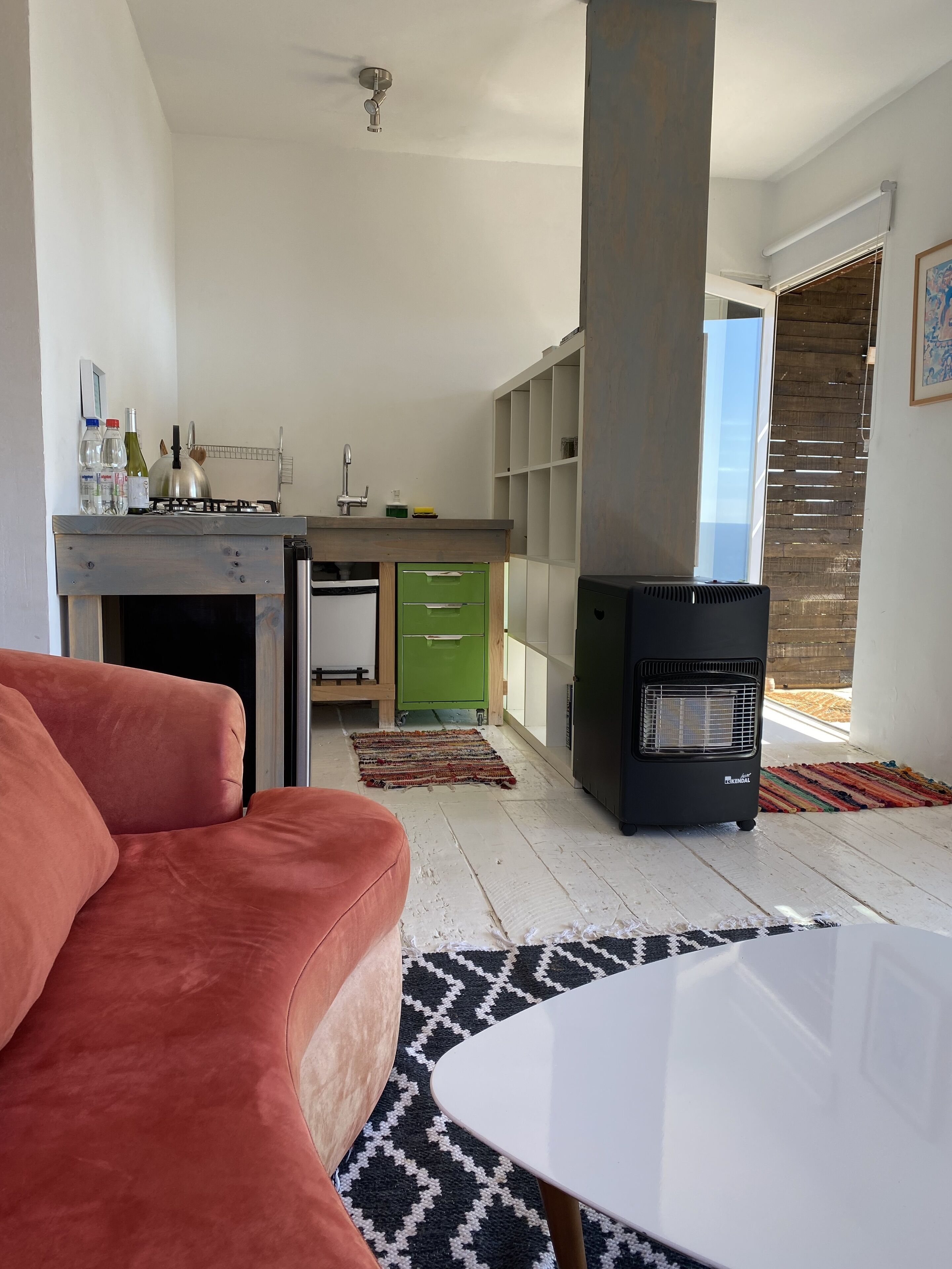 Um espaço de estar moderno com sofá, mesa, cozinha com fogão a gás e lareira a lenha.
