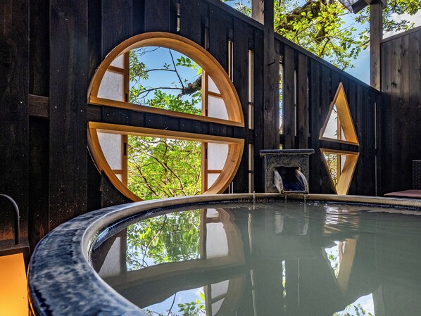 Uma área de spa com hidromassagem, paredes de madeira e janelas amplas.