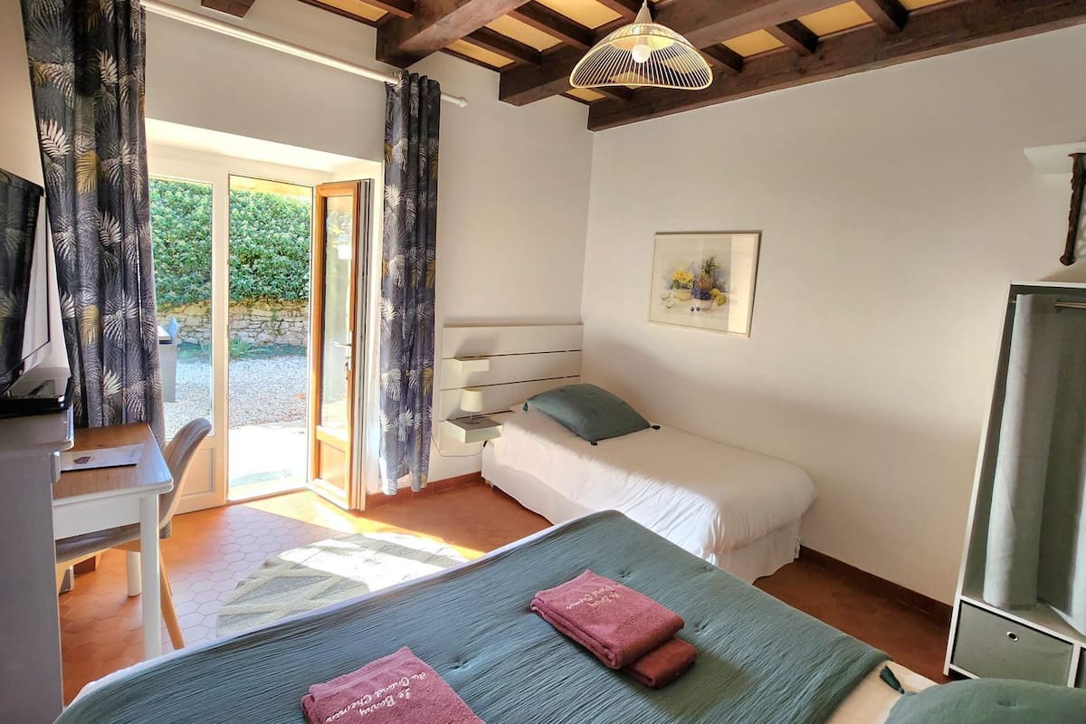 Quarto com cama, escrivaninha e janela com cortinas.
