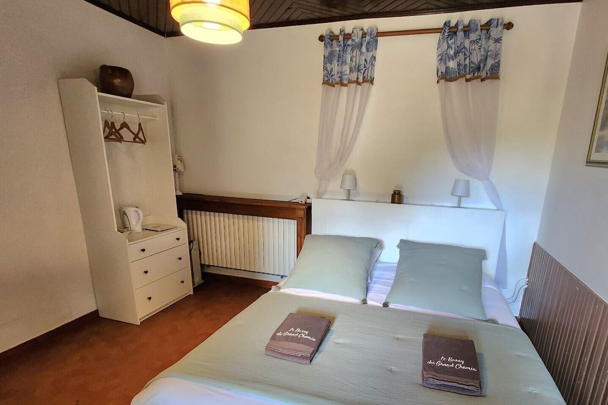 Quarto com cama, mesas de cabeceira, guarda-roupa e radiador.