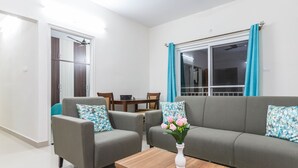 Uma sala de estar moderna com dois sofás cinza, uma mesa de centro de madeira e uma pequena mesa com um vaso de flores.
