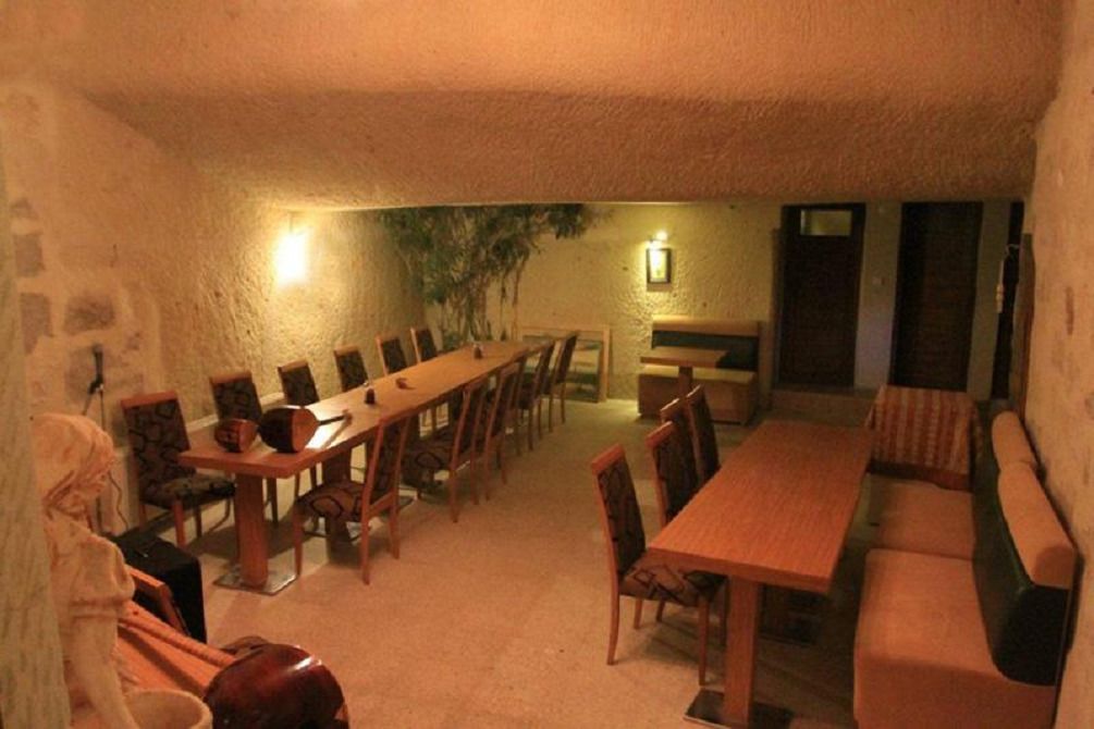 Uma sala de jantar com uma mesa de madeira comprida e cadeiras, um sofá e uma mesinha com abajur.