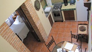 Uma cozinha com fogão a gás, geladeira e área de jantar com mesa e cadeiras.