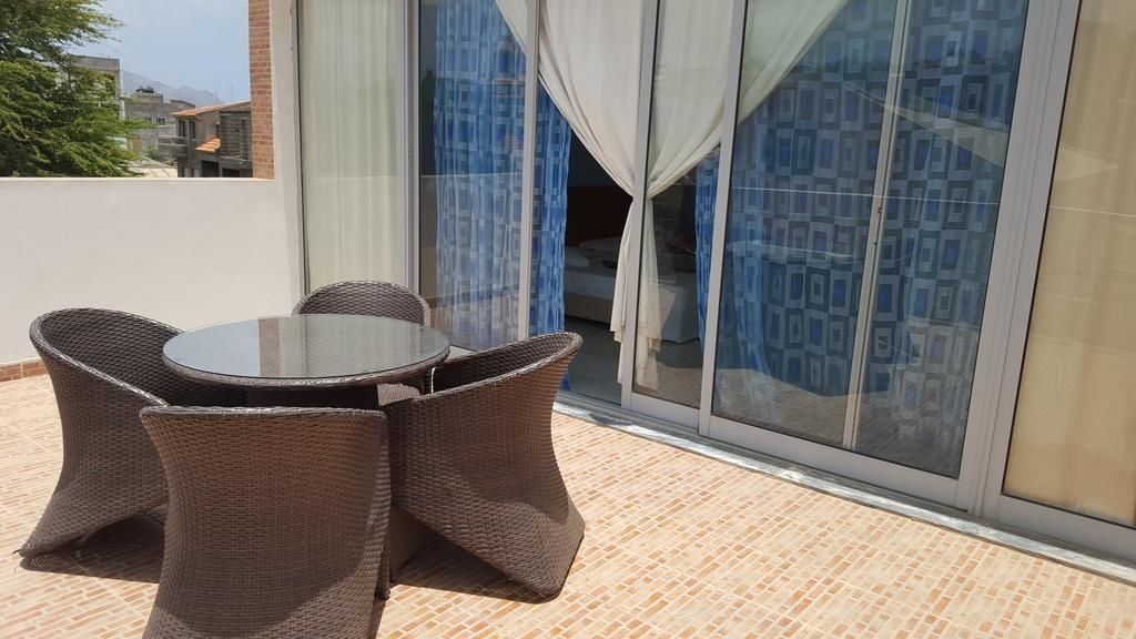 Varanda com móveis de vime e porta de vidro que dá para um quarto.
