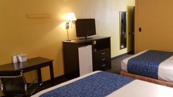 Quarto de hotel com duas camas, uma escrivaninha, uma televisão e um espelho.