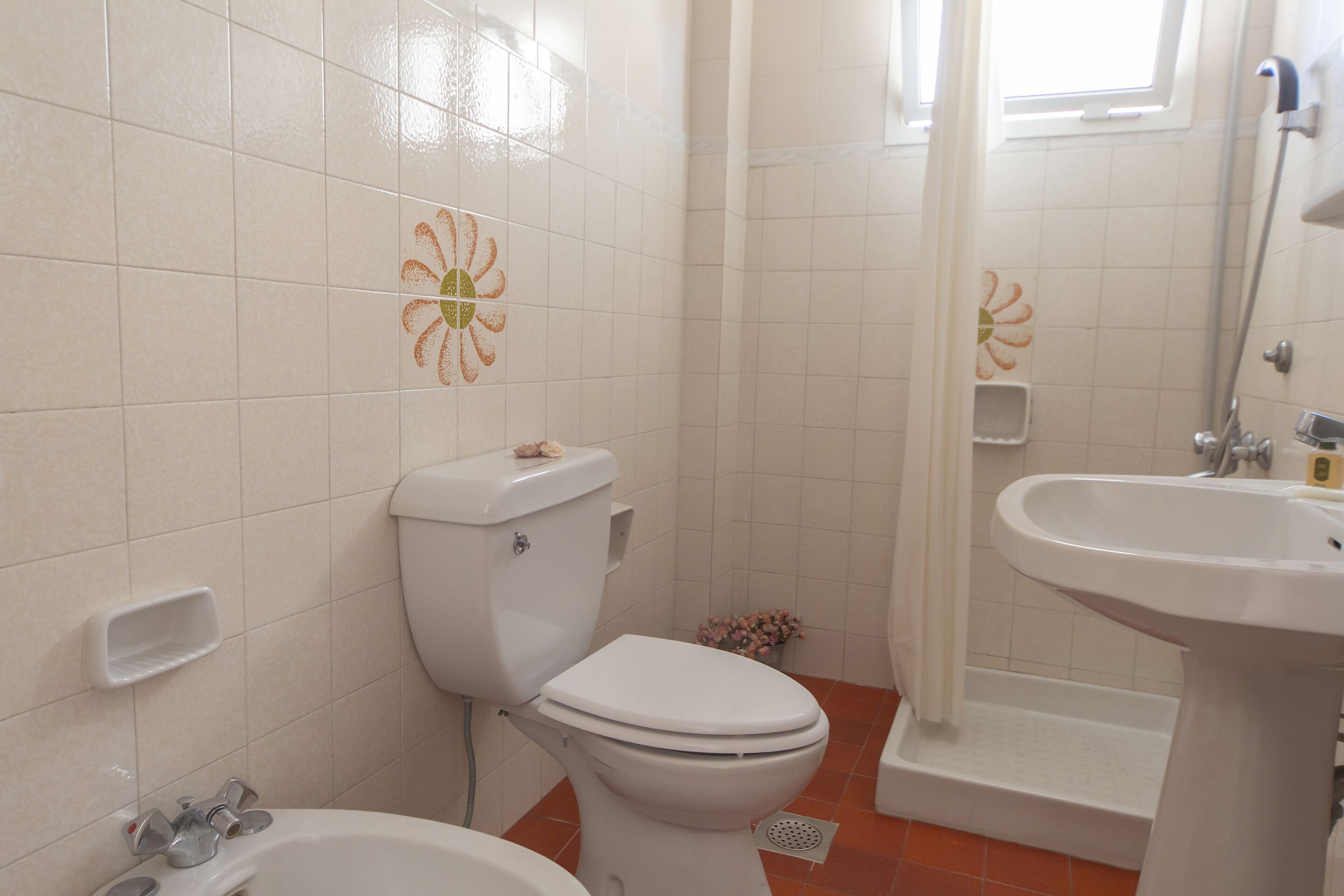 Casa de banho com sanita, bidé, lavatório e chuveiro.