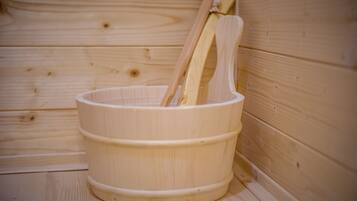 Uma sauna de madeira com um balde e uma concha de madeira.