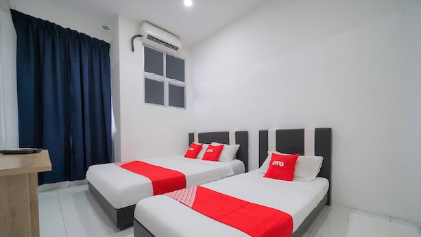 Quarto de hotel com duas camas, uma mesa, uma janela e ar condicionado.