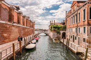 Um canal estreito com barcos, uma ponte e edifícios com arquitetura tradicional.