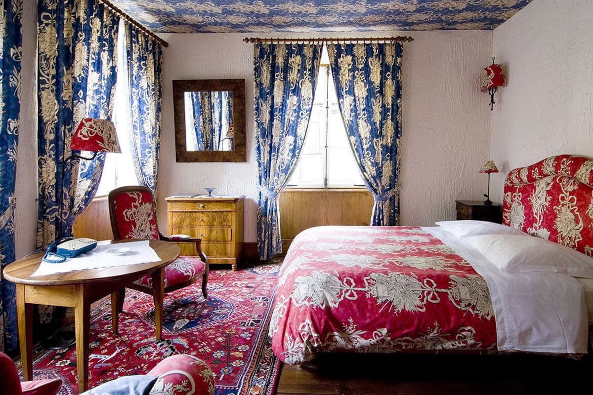 Um quarto tradicional com uma cama, penteadeira de madeira, uma cadeira, uma mesa e um espelho.