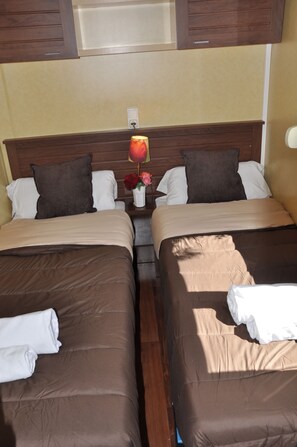 Uma cama de casal com cabeceira de madeira, duas almofadas e um vaso com flores.