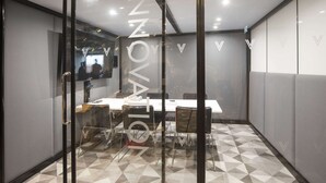 Uma sala de reunião moderna com divisória de vidro, uma mesa branca e várias cadeiras.