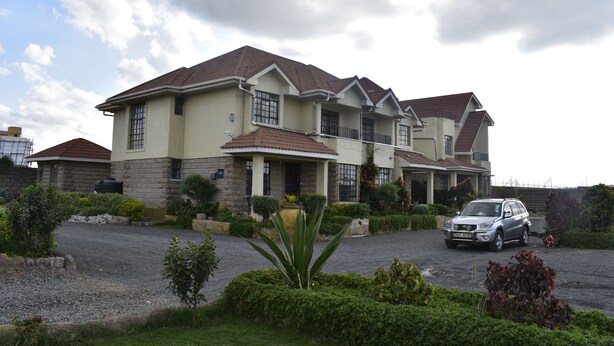 Uma casa grande de dois andares com entrada de automóveis e um carro estacionado.