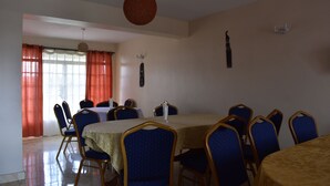 Uma área de refeições com uma mesa e cadeiras, um lustre pendurado e uma janela com cortinas.