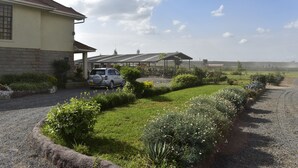 Um imóvel residencial com casa, área externa coberta e entrada com calçamento de brita.
