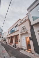 Um hotel com fachada moderna, sinalização com 'HOTEL INSOMNIA' e um sinal de elevador visível.