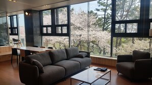Uma sala de estar moderna com uma janela grande, um sofá, uma mesa de centro e um espaço para refeições.