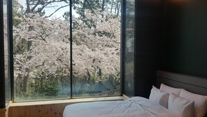 Quarto com uma janela grande, uma cama e uma mesa de cabeceira.