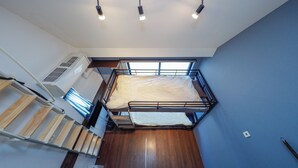 Quarto compacto com cama de solteiro, janela com vista e ar condicionado.