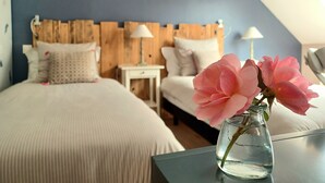 Quarto com cama, mesa de cabeceira e um vaso com flores.
