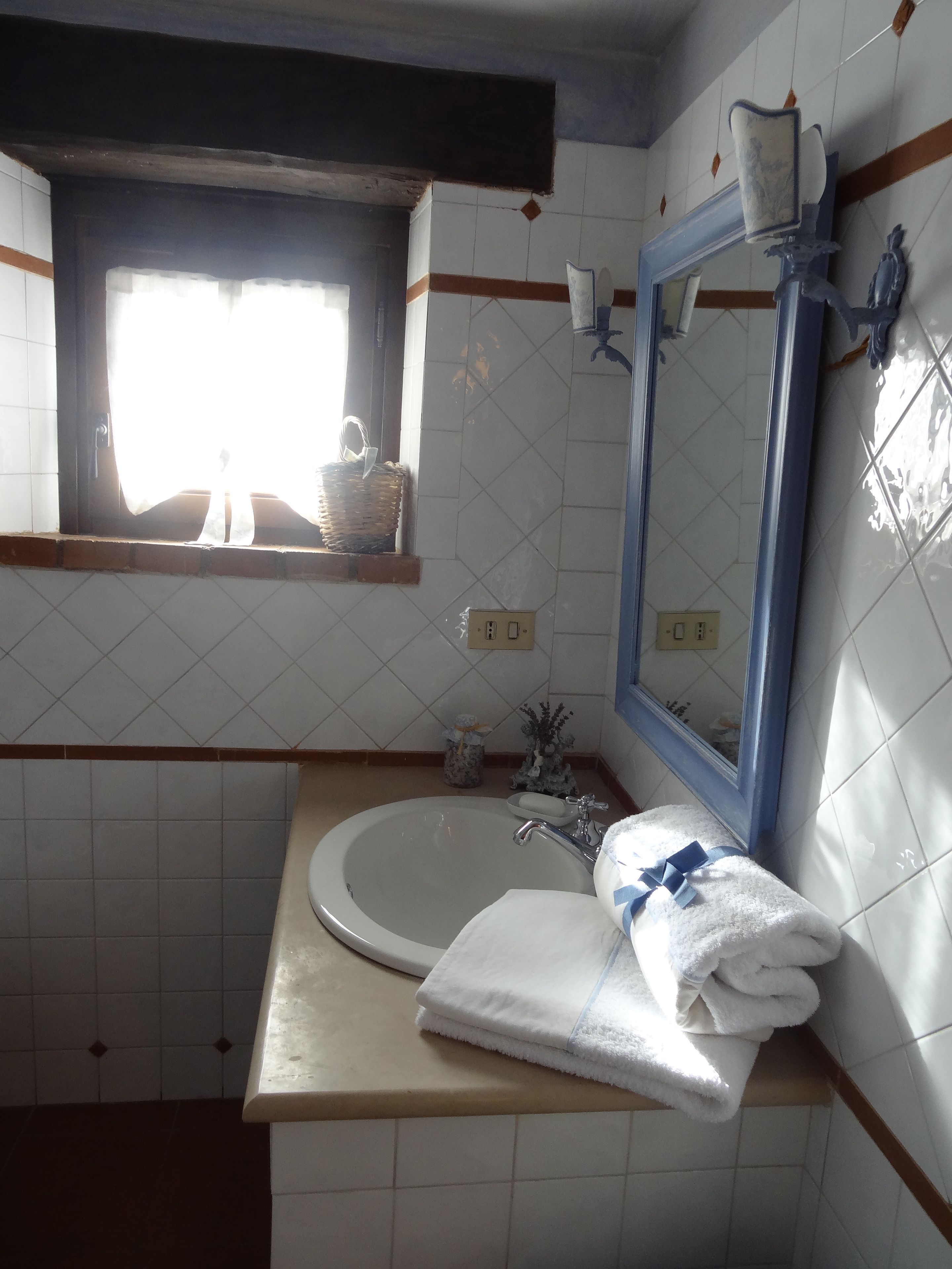Casa de banho com lavatório, espelho e janela.