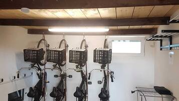 Quarto com teto de madeira, bicicletas fixadas na parede, uma janela e um varal.