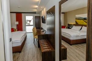 Quarto de hotel com duas camas, uma escrivaninha, uma cadeira, uma televisão e um espelho grande.