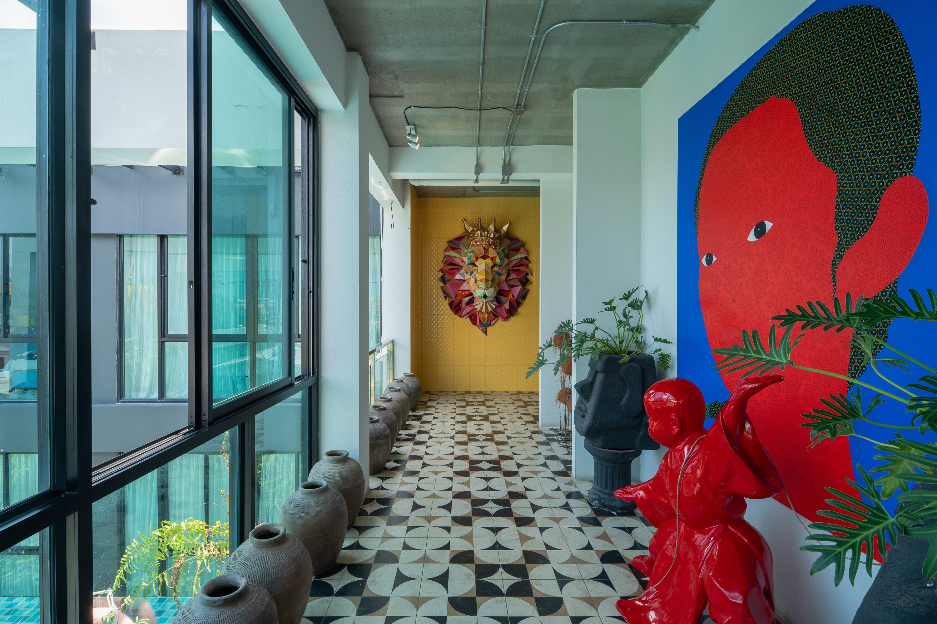 Um corredor com piso estampado, grandes janelas e um mural colorido na parede.
