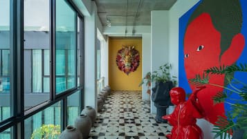 Um corredor com piso estampado, grandes janelas e um mural colorido na parede.