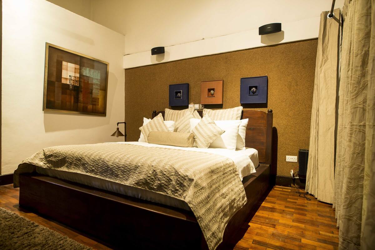 Quarto com uma cama grande, cabeceira de madeira e um quadro emoldurado na parede.