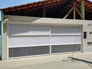 Uma garagem com portão de metal, parede revestida de azulejos e o número '315' na lateral.