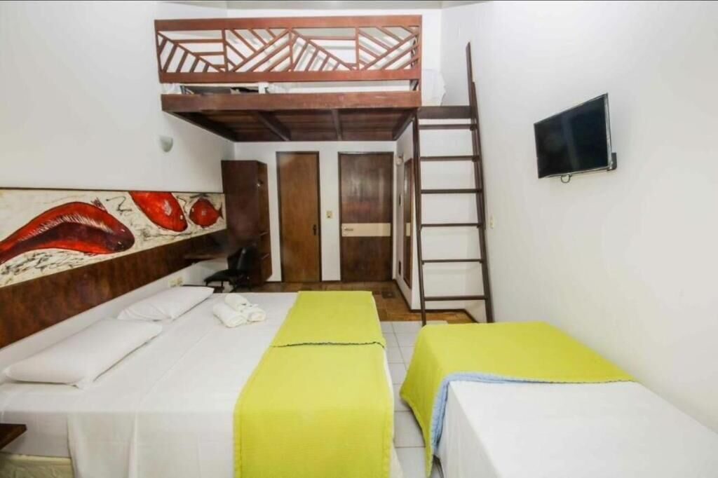 Quarto com duas camas, uma cama beliche, uma televisão e uma escada.