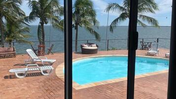 Área da piscina com espreguiçadeiras e vista para o oceano.