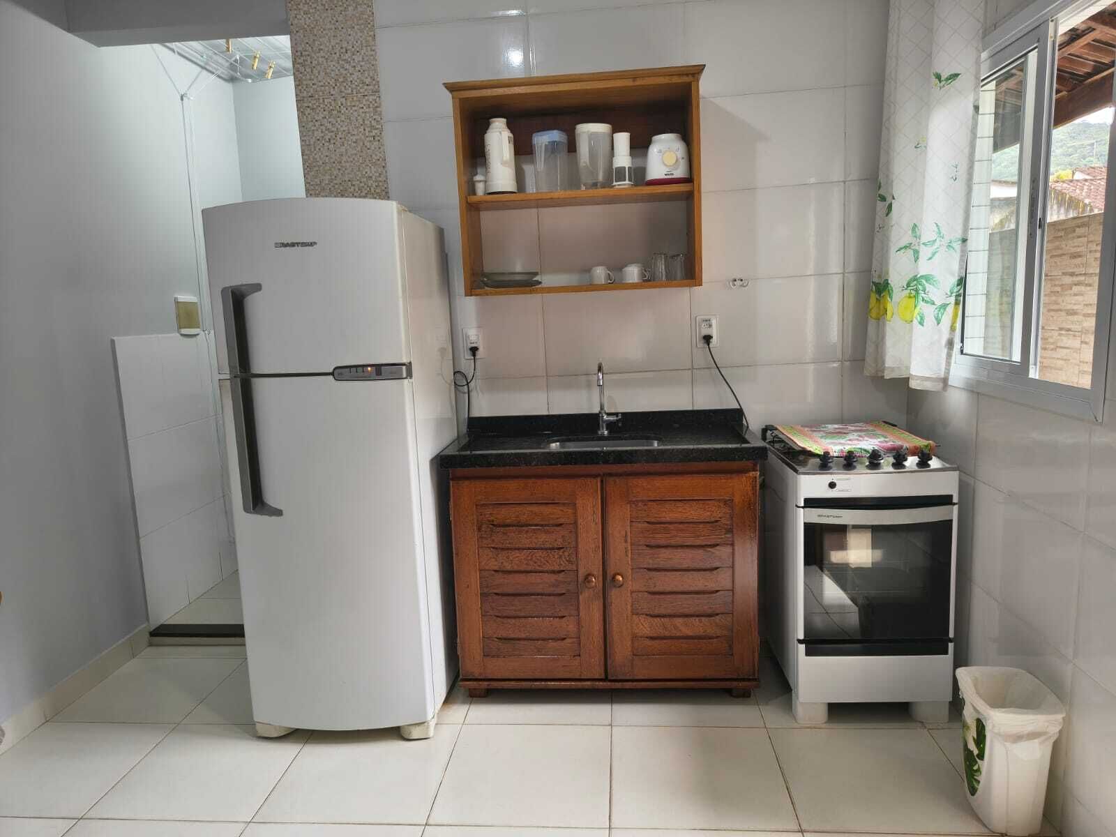 Uma cozinha compacta com geladeira, armário de madeira, pia e fogão.