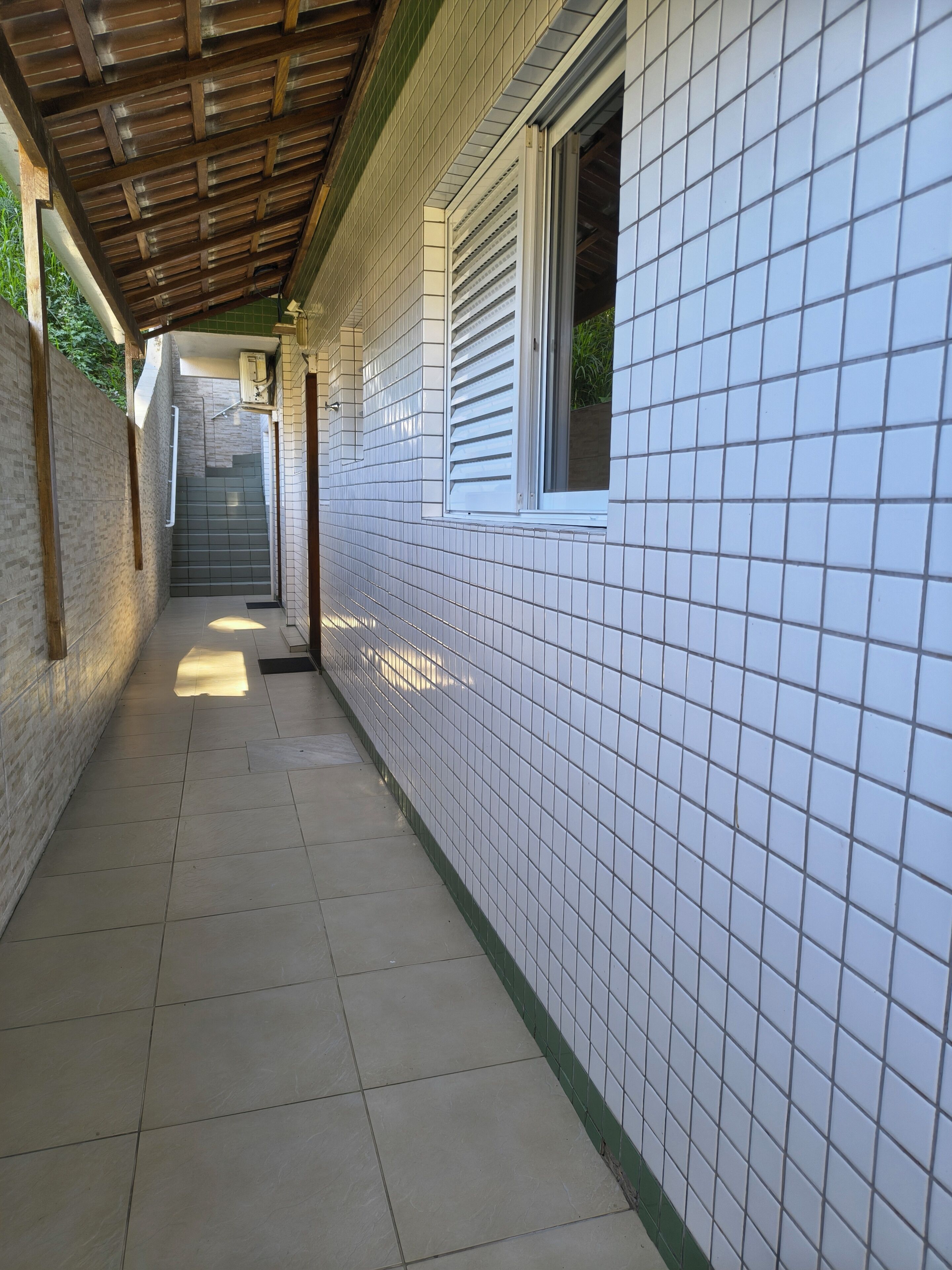 Um corredor com paredes revestidas de azulejos e teto de madeira, que leva a uma porta.