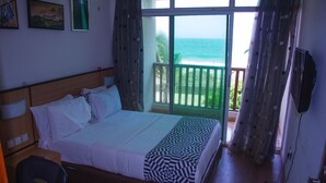 Quarto de hotel com cama, televisão, mala e varanda com vista para o oceano.