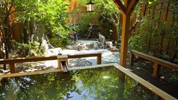 Um jardim tranquilo com um deck de madeira, um lago de carpas e uma cascata.