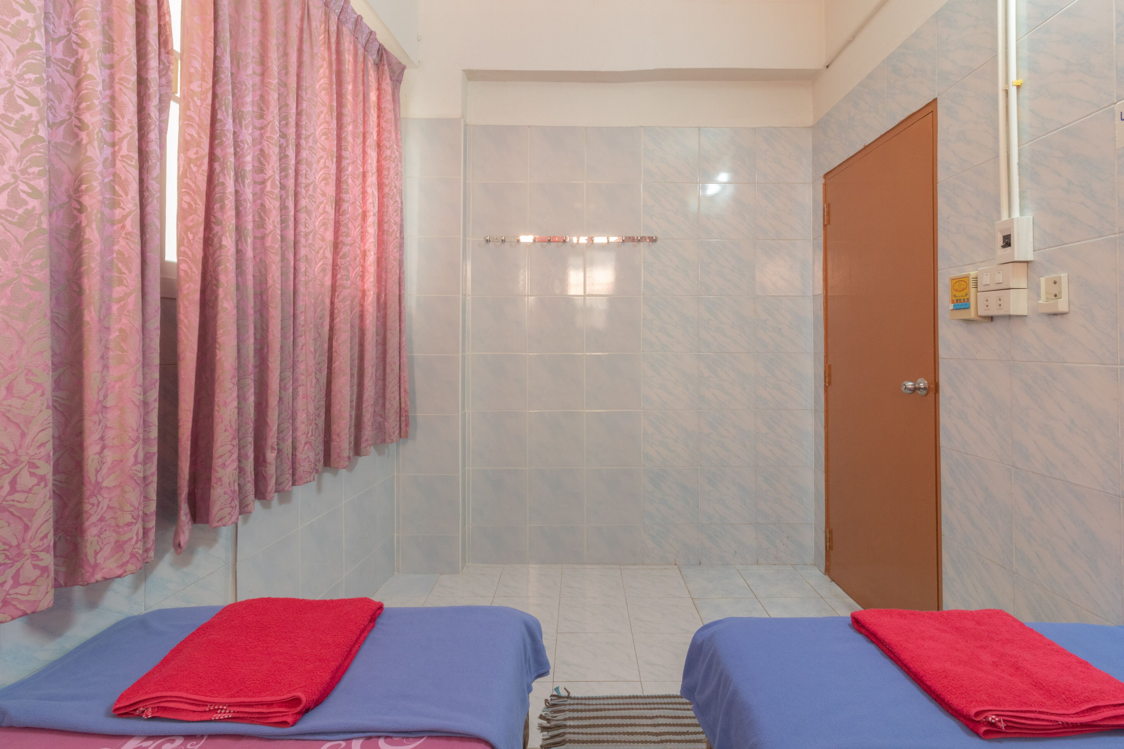 Quarto de hotel com duas camas, área de chuveiro e uma porta.