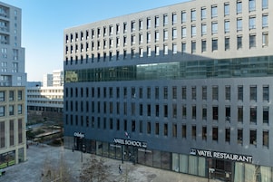 Um edifício moderno com vários andares, exibindo uma placa grande com a inscrição 'Vatel School' e outra placa com 'Vatel Restaurant'.
