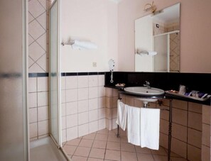 Casa de banho com lavatório, espelho, toalheiro e zona de duche.
