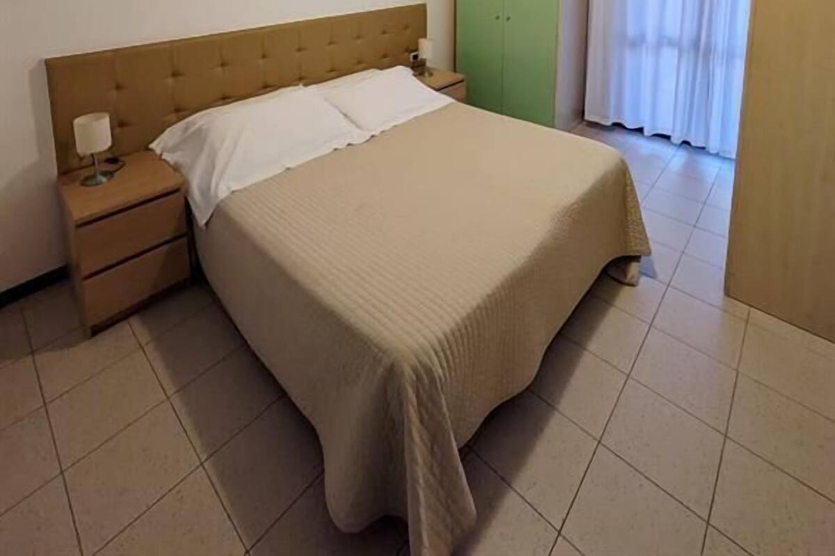 Quarto com cama, mesa de cabeceira e guarda-roupa.